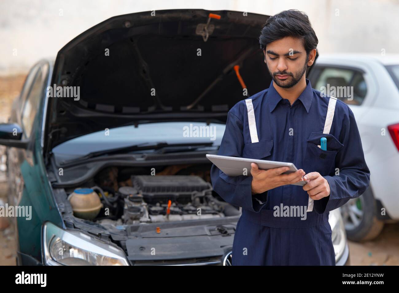 A MECHANIC USING A DIGITAL TABLET TO CHECK THE WORKING OF A CAR Stock ...