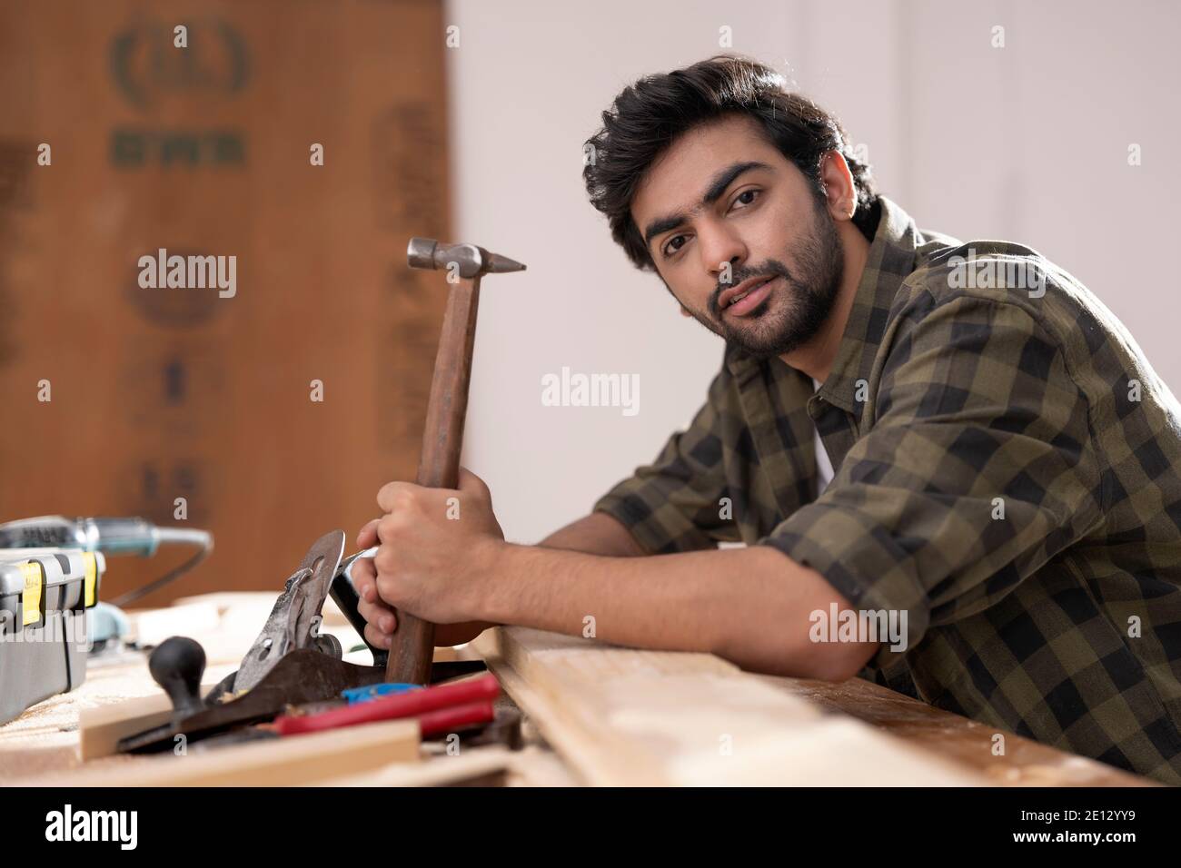 A CARPENTER HOLDING HAMMER SITTING AND LOOKING AT CAMERA Stock Photo ...