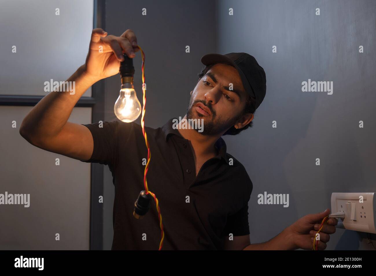 AN ELECTRICIAN HOLDING BULB AND TESTING LIGHT Stock Photo - Alamy