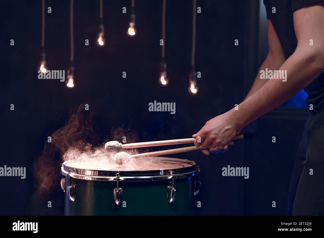 The percussionist plays with sticks on the floor tom in a dark room ...