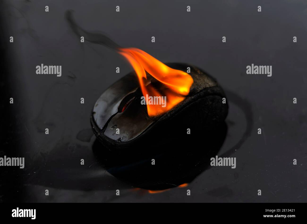 Burning wireless computer mouse on a black table. Close-up of a laptop ...