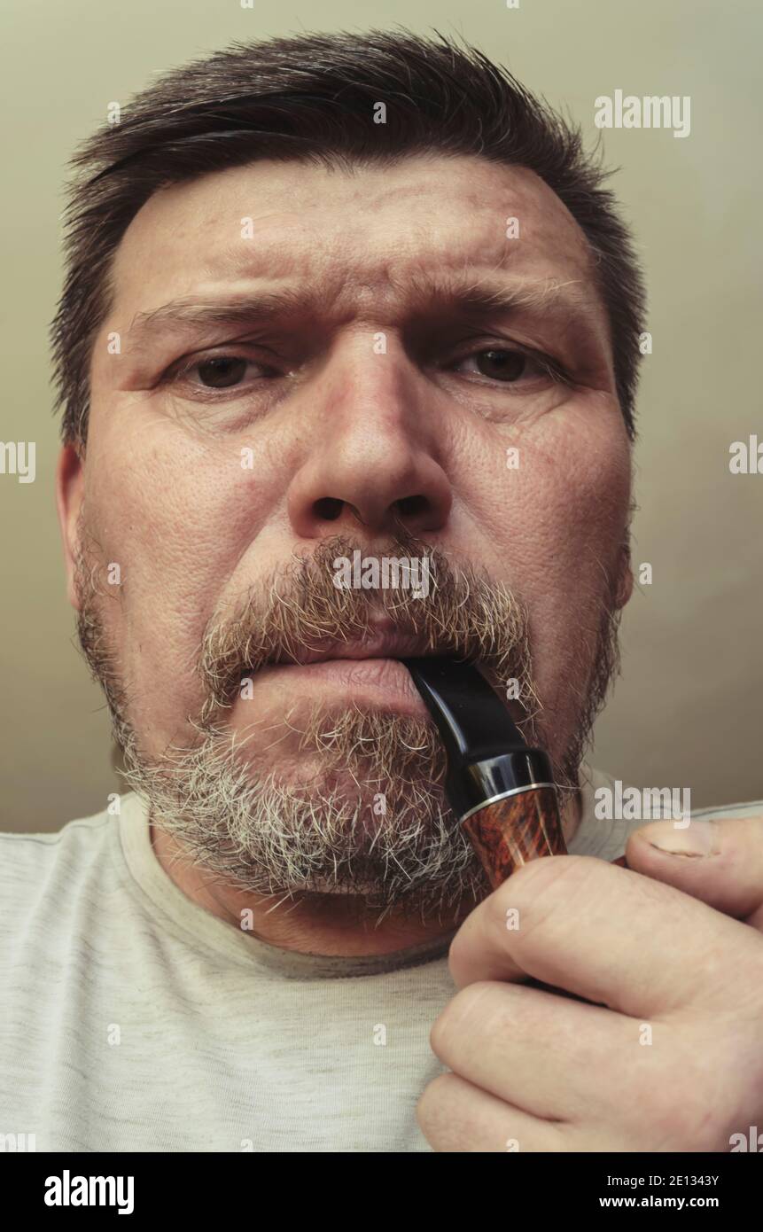 Unusual portrait of a bearded man with a smoking pipe in his mouth. A ...
