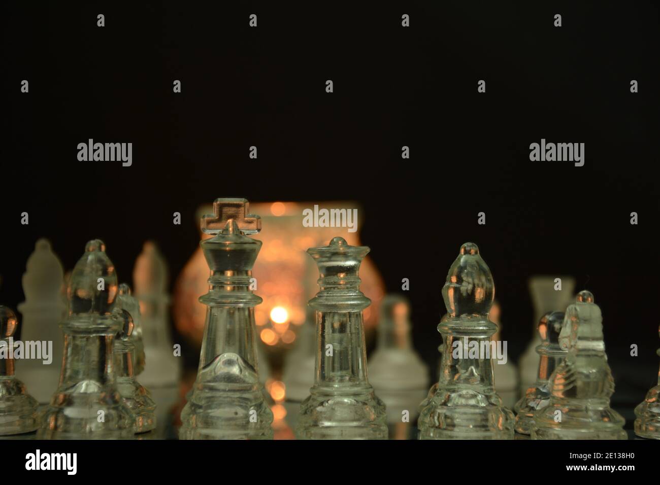 Clear glass chess pieces on a glass chessboard isolated on a black ...