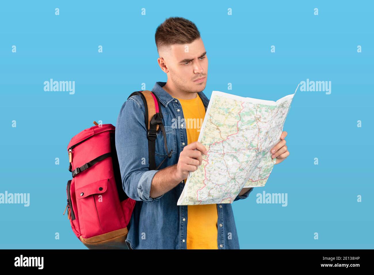 Pensive young backpacker looking at map with concern, feeling lost ...