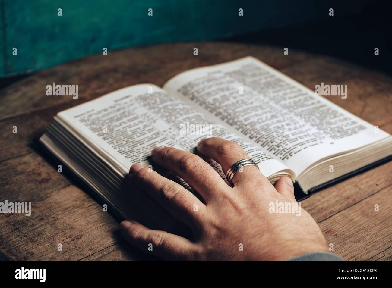 Man sitting at a reading the Holy Bible on a old oak wooden table and ...