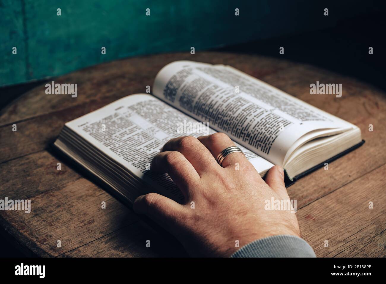 Man sitting at a reading the Holy Bible on a old oak wooden table and ...