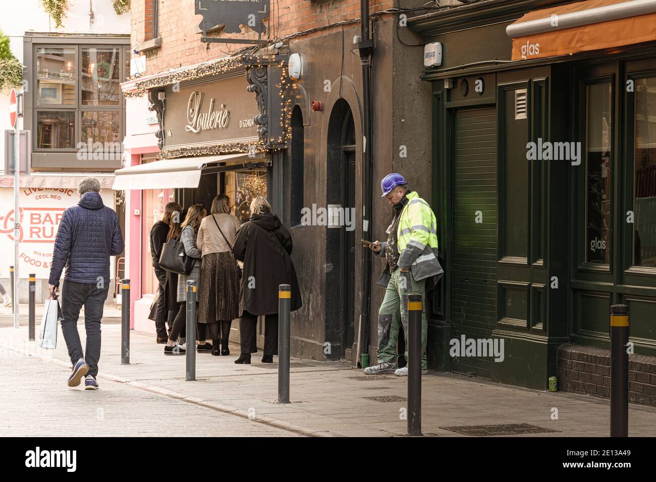 Man in construction clothing and women looking into jewellery shop ...