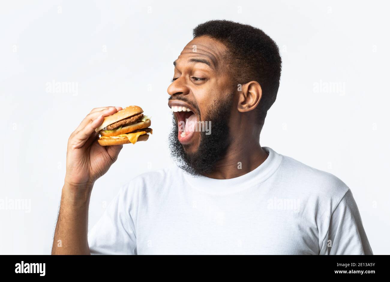 Hungry African American Guy Eating Burger Standing Over White ...
