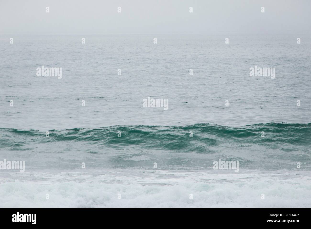 Minimalist image of a smooth wave coming ashore on a foggy day, with a ...
