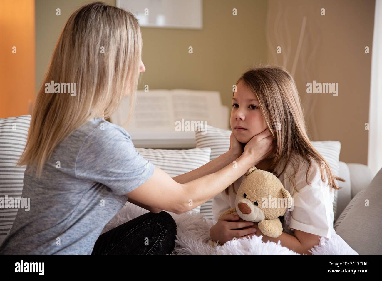 Mom checks her sick daughter's throat and fever Stock Photo - Alamy