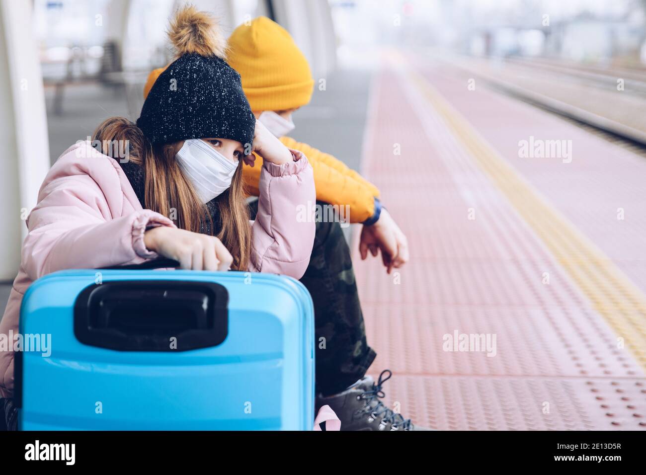 Sad children are sitting on the platform of the train station wanting ...