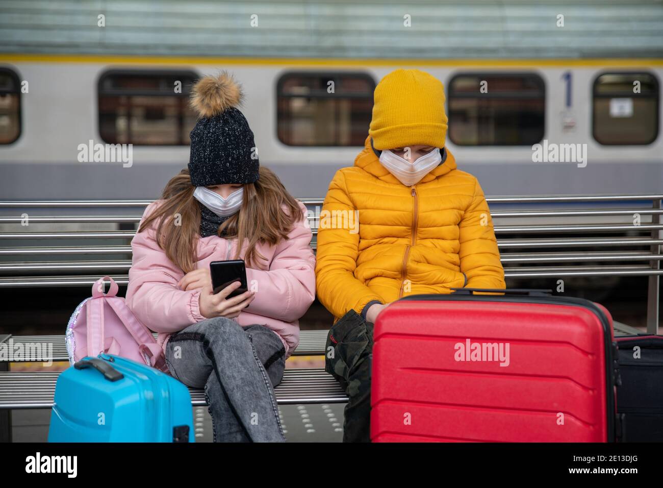 Two bored children in protective masks during the pandemic are waiting ...