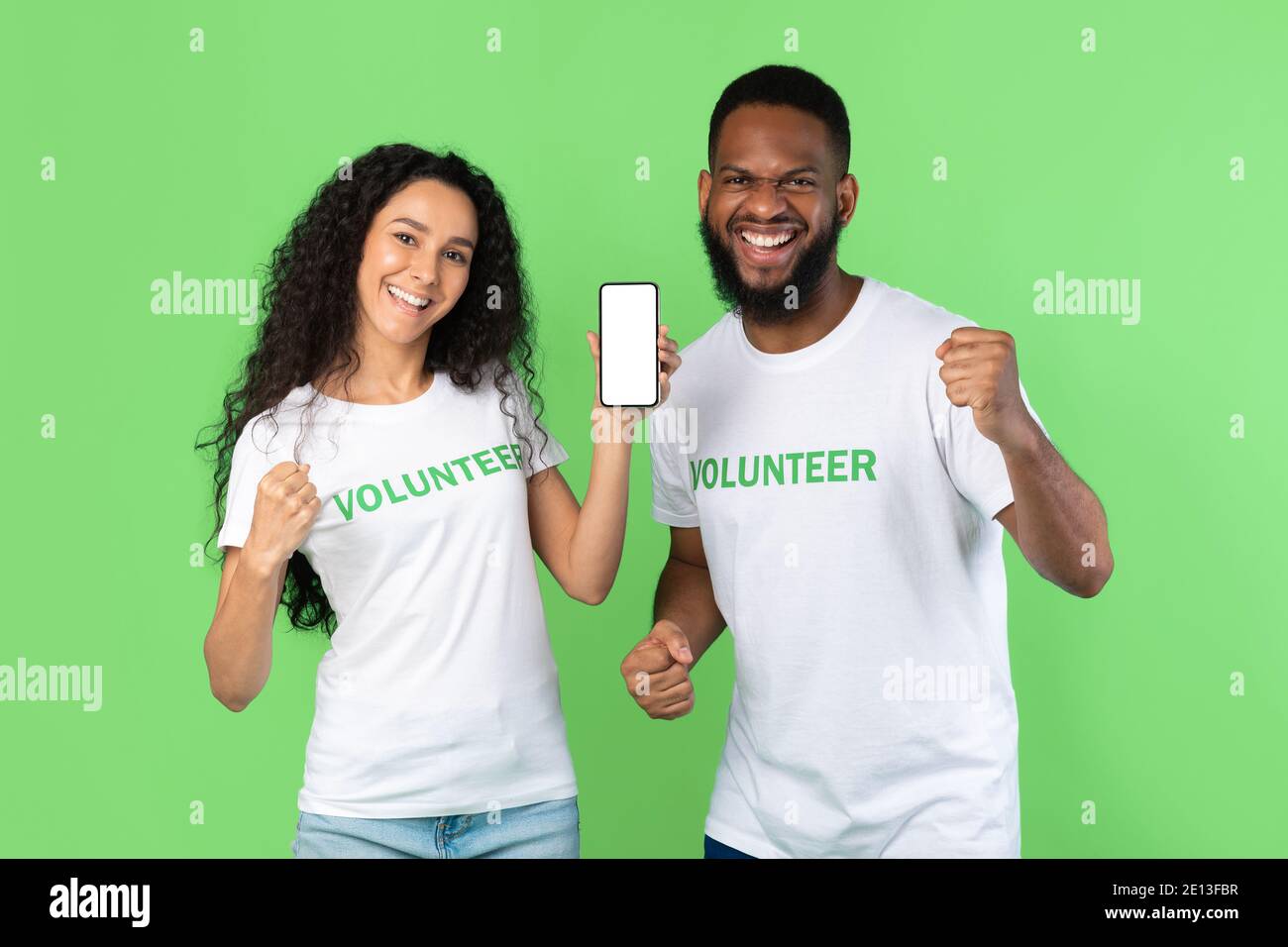Two Volunteers Showing Phone Screen Gesturing Yes On Green Background ...
