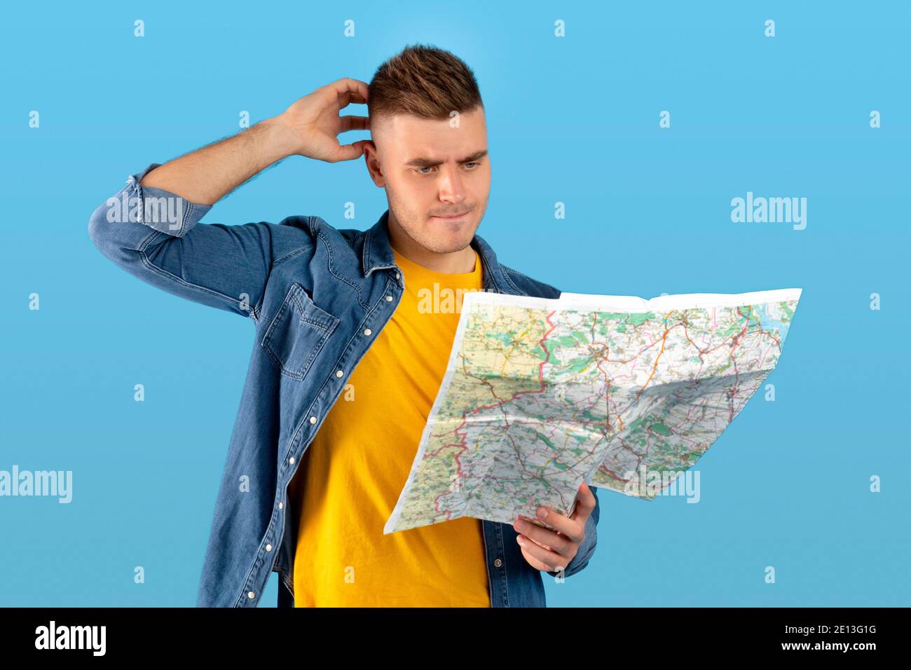 Frustrated man examining map and scratching head, feeling lost, having ...