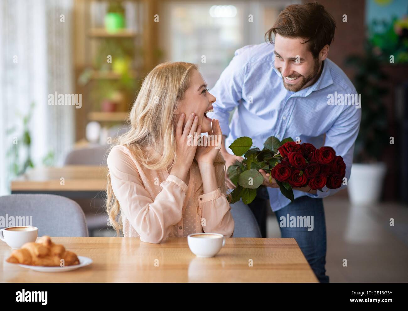 Celebrating special occasion. Romantic young guy presenting bouquet of ...