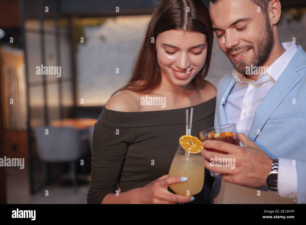 Cropped shot of a young couple cuddling at the bar, while drinking ...