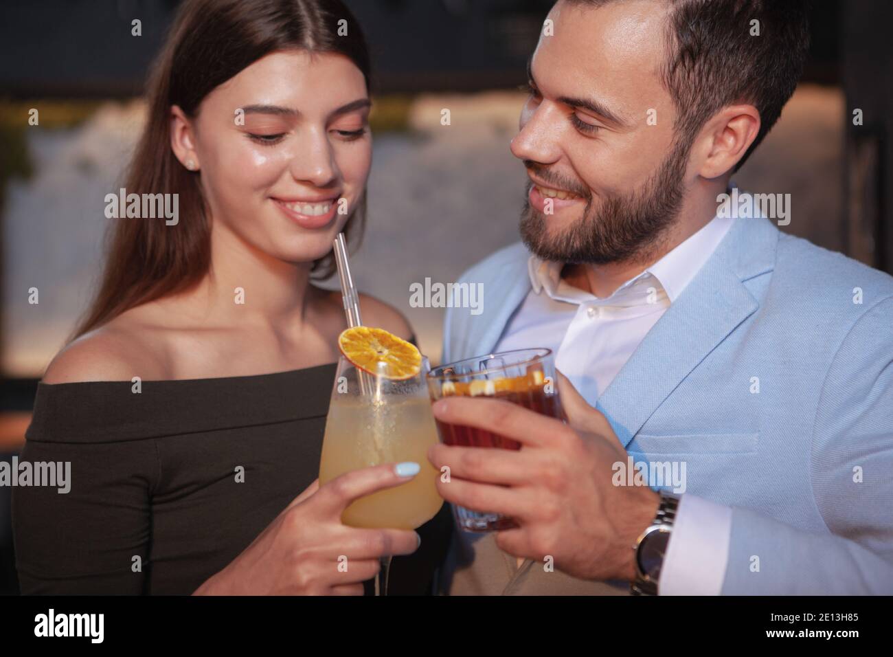 Cropped close up of happy young couple clinking cocktail glasses ...