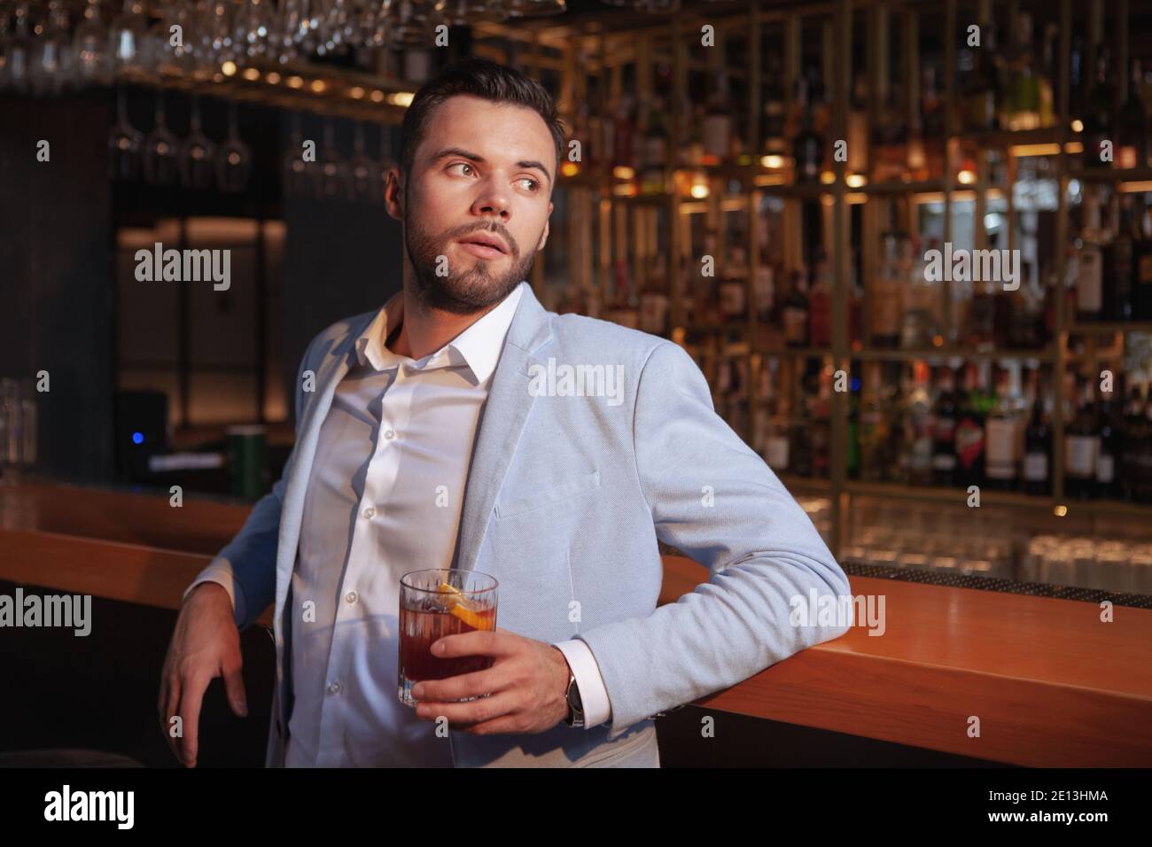 Handsome elegant young man relaxing at cocktail bar, leaning on bar ...