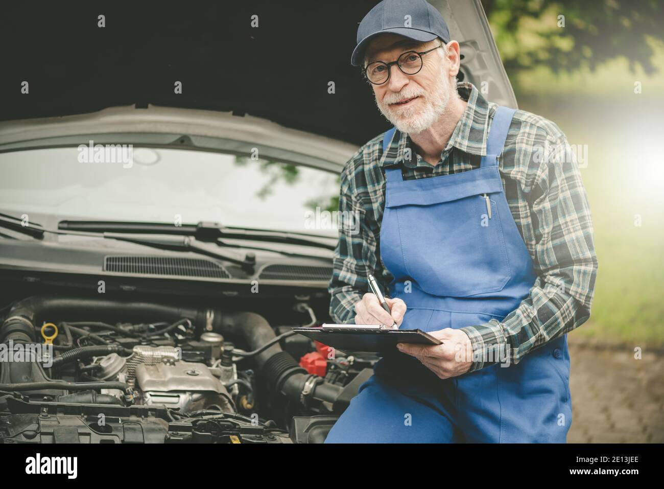 Car mechanic checking a car engine and writing on clipboard Stock Photo ...