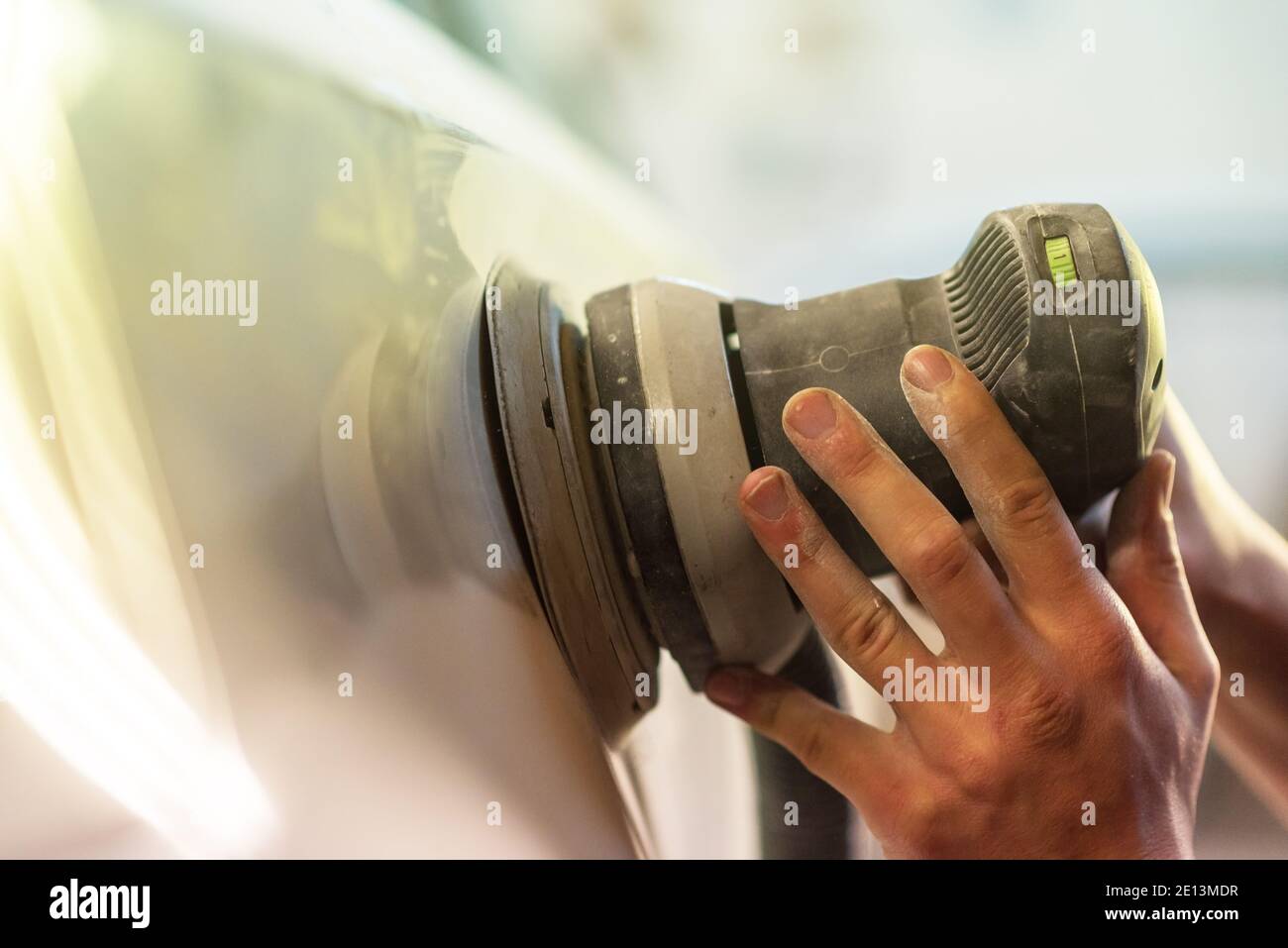 Grinder in the hands of a man who sharpen a car varnish in the car shop ...