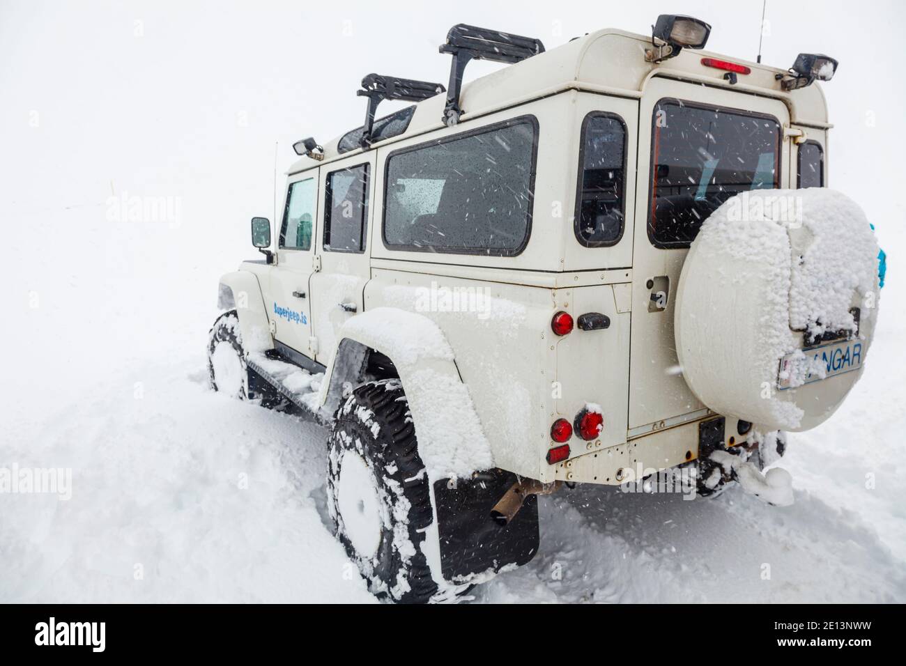 A white Land Rover Defender 4v4 4WD vehicle in heavy snow on a tourist ...
