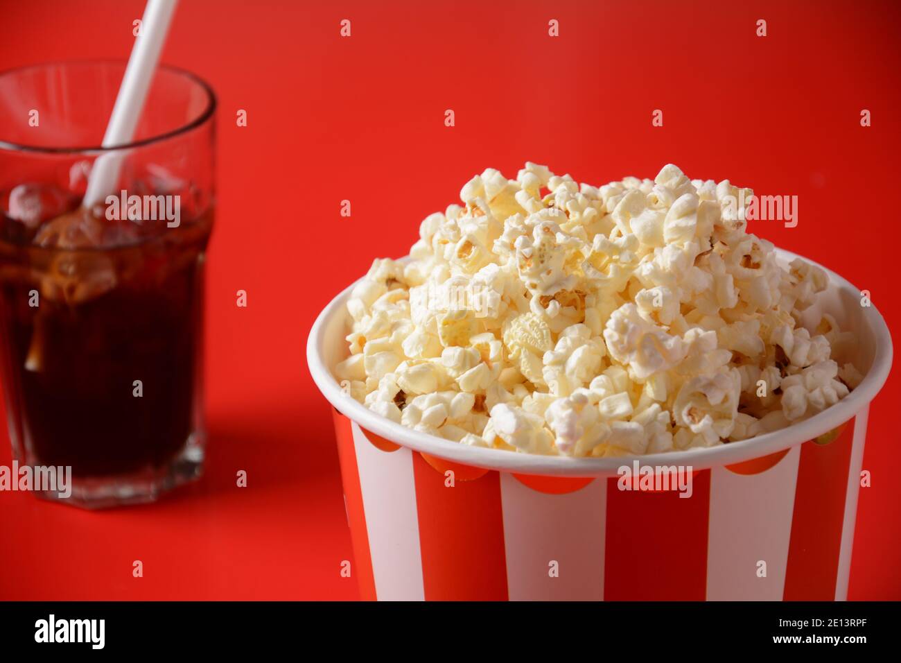 Buckets with delicious popcorn on red background and a glass of Coca ...