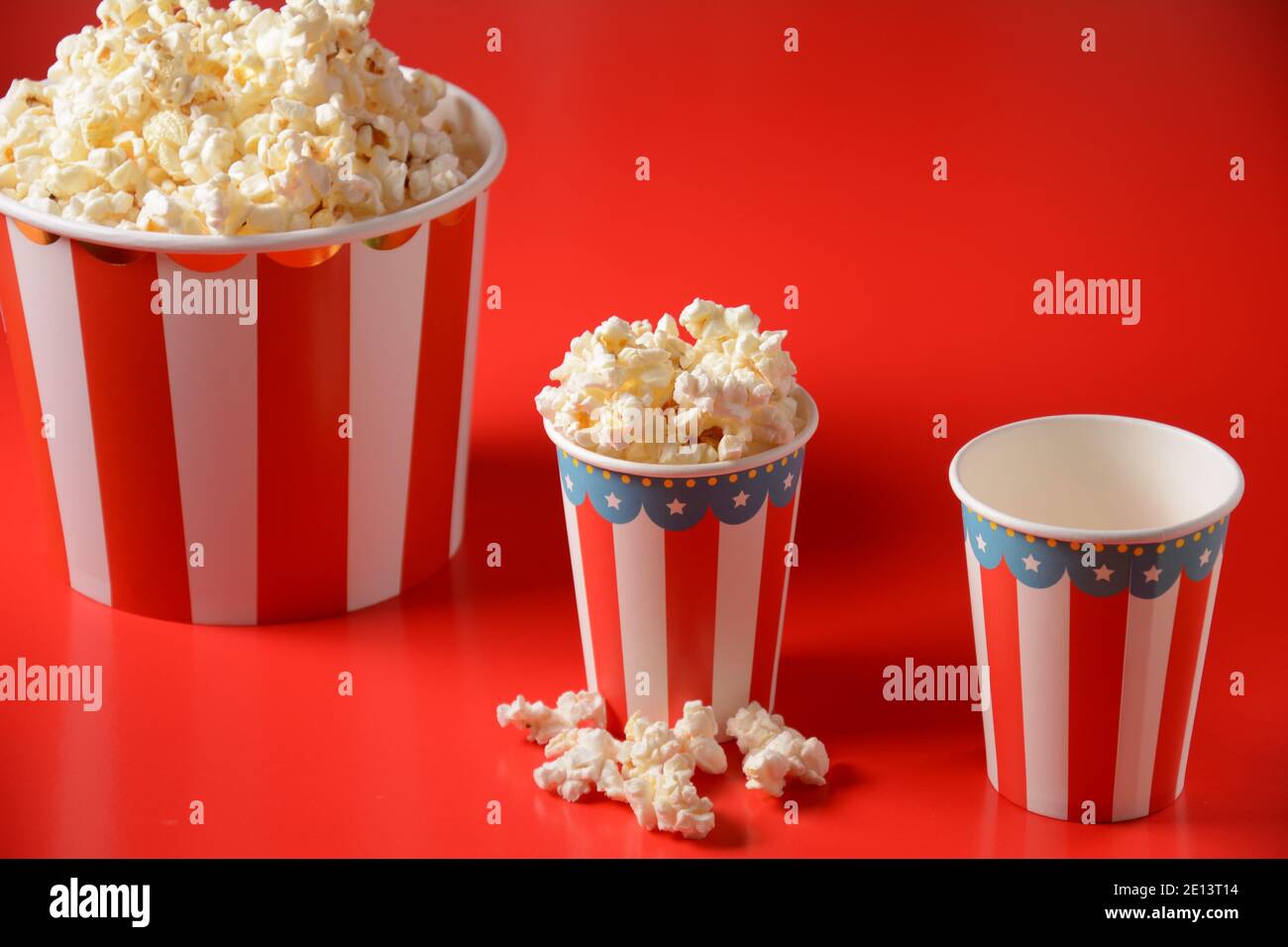 Buckets with delicious popcorn on red background. Spilled popcorn Stock ...