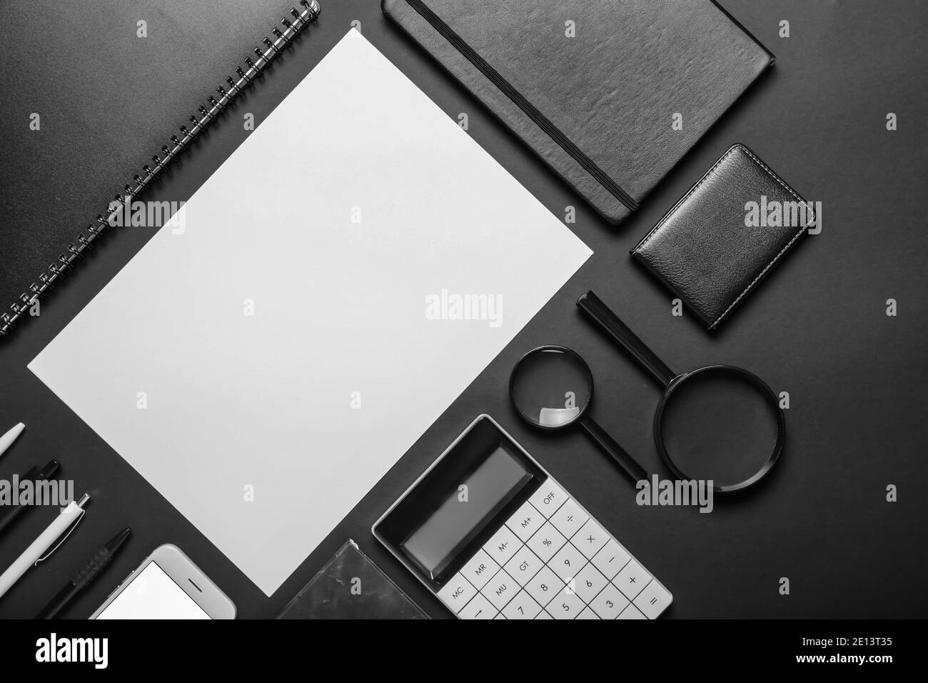 Composition with blank paper sheet and stationary on dark background ...