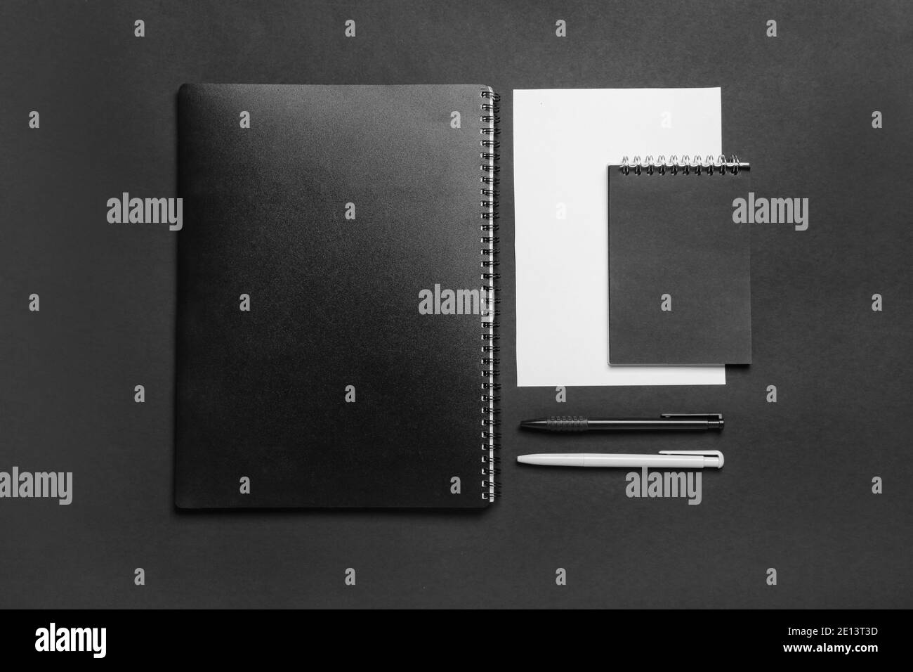 Composition with blank paper sheet, notebooks and pens on dark ...