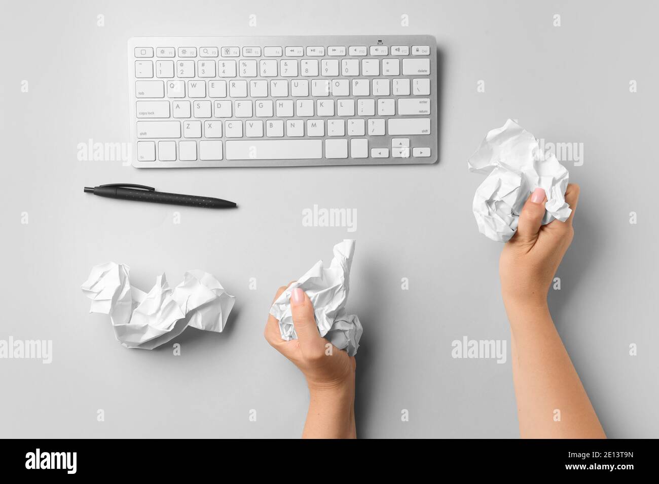 Female hands with crumpled paper, pen and keyboard on light background ...