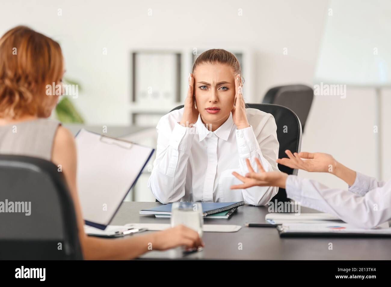 Stressed woman with headache and noisy people in office Stock Photo - Alamy