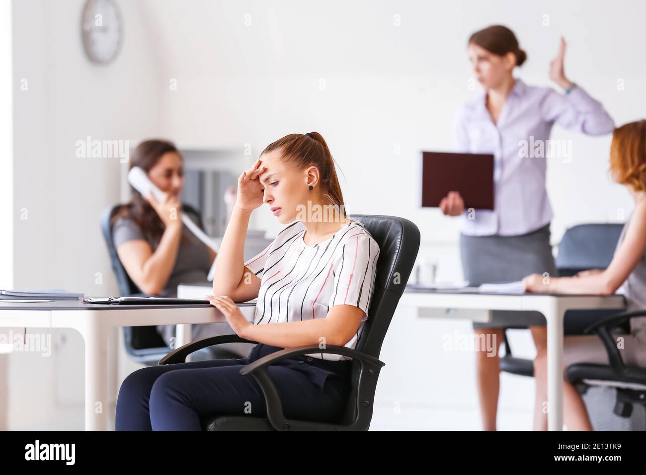Stressed woman with headache and noisy people in office Stock Photo - Alamy