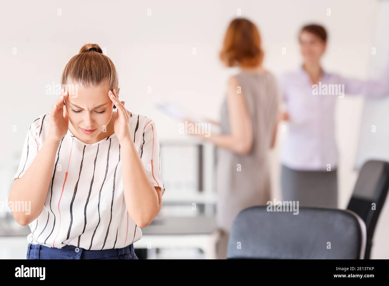 Stressed woman with headache and noisy people in office Stock Photo - Alamy