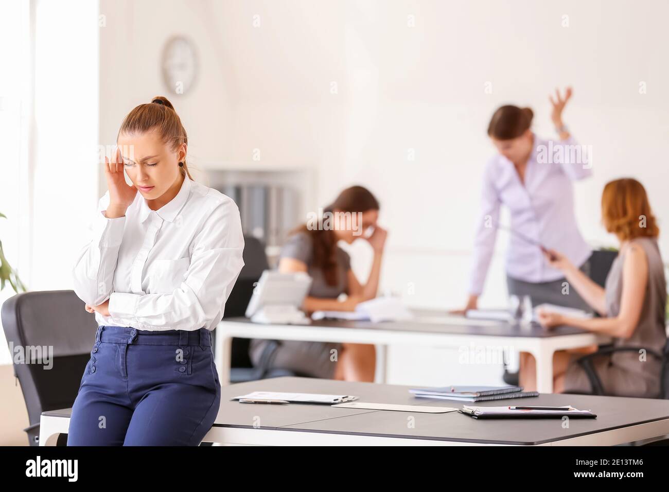 Stressed woman with headache and noisy people in office Stock Photo - Alamy