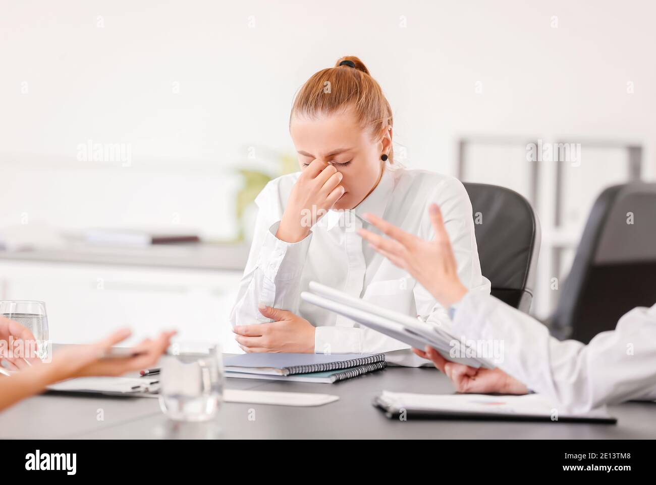 Stressed woman with headache and noisy people in office Stock Photo - Alamy