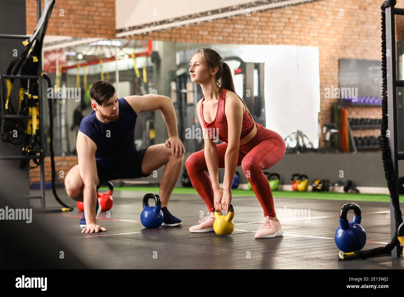 Sporty young woman training with coach in gym Stock Photo - Alamy