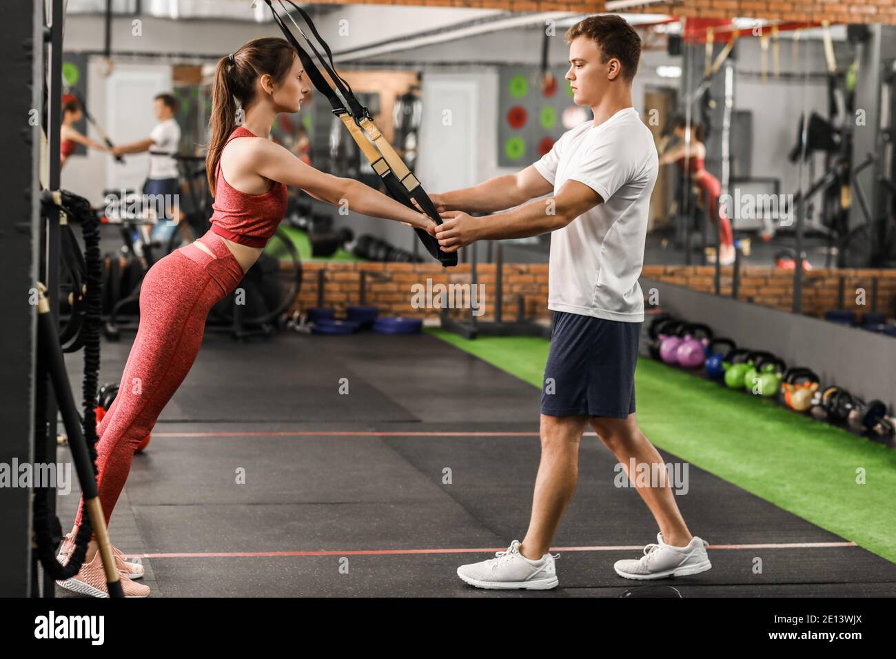 Sporty young woman training with coach in gym Stock Photo - Alamy