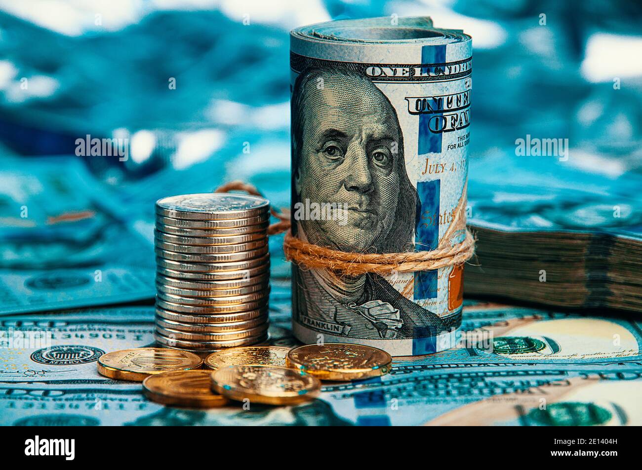 A roll of one hundred dollar bills and gold coins on the scattered ...