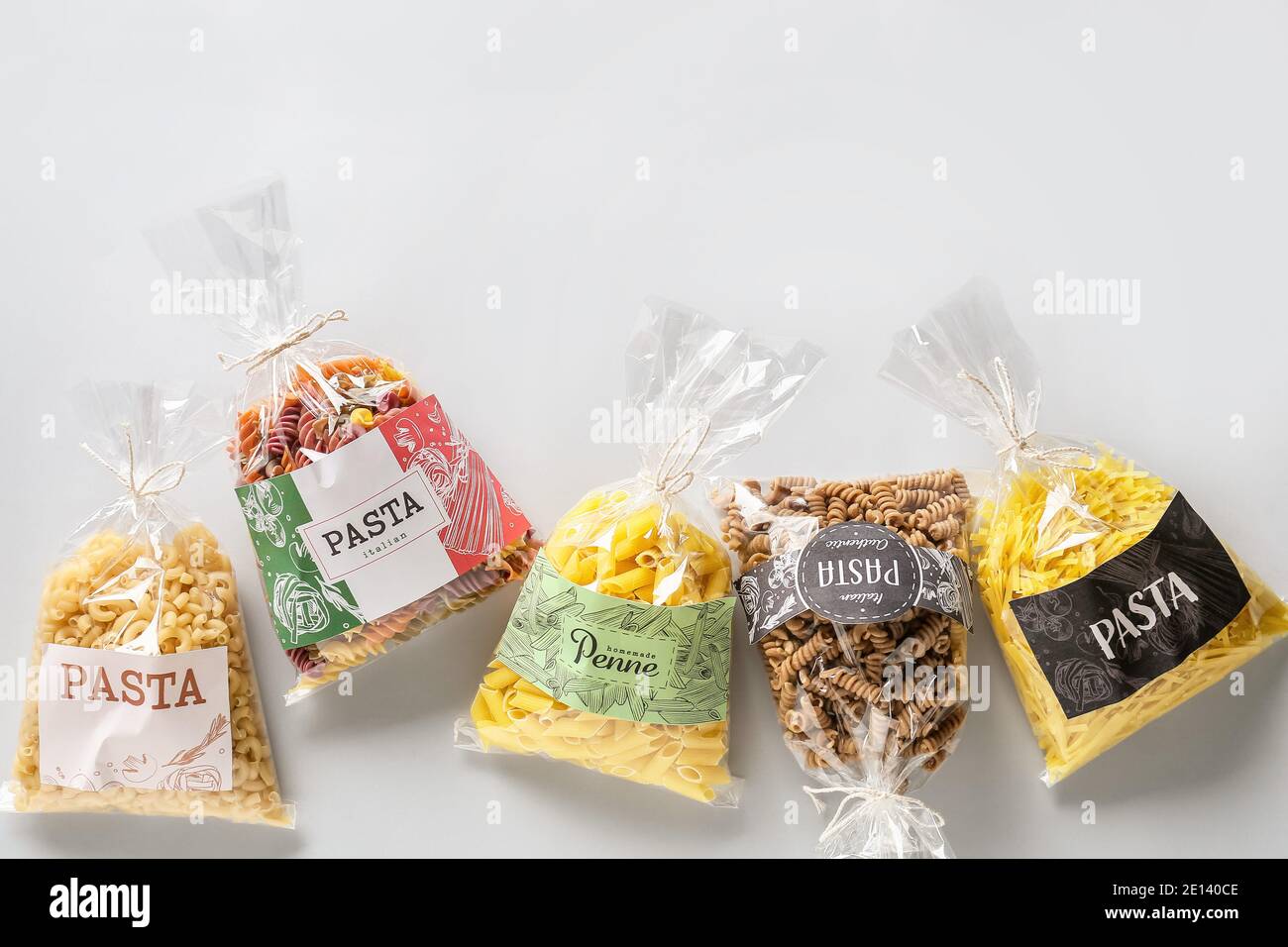Bags with uncooked pasta on white background Stock Photo - Alamy