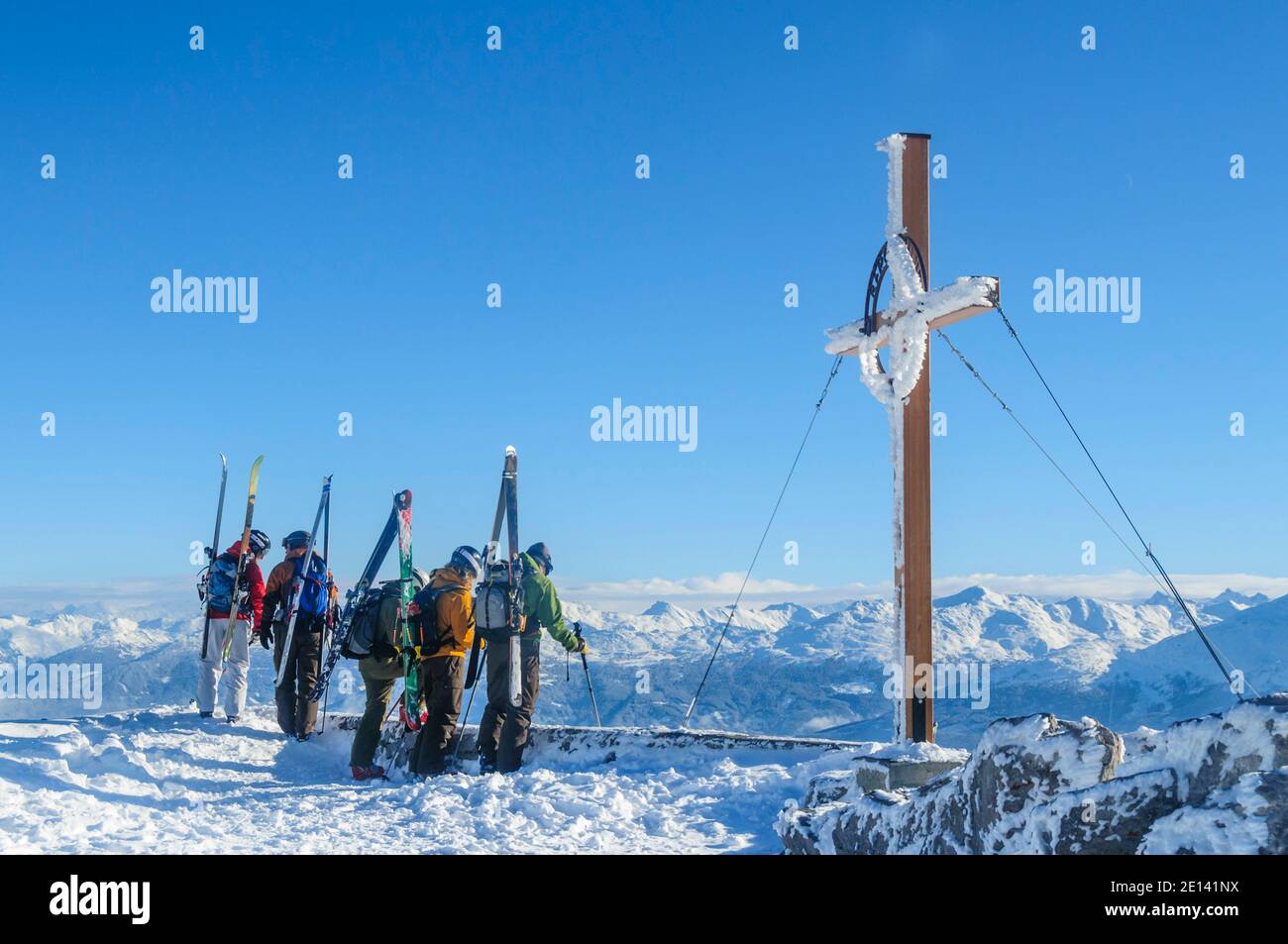 A group of Freeriders standing at a summit cross on mountain top of the ...