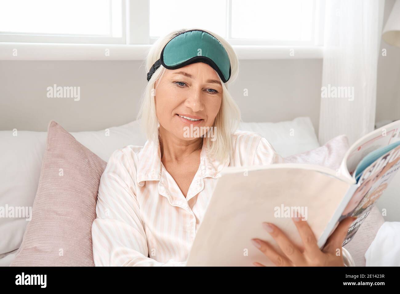 Mature woman reading magazine in bedroom Stock Photo - Alamy
