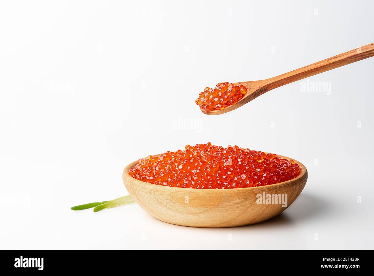 Red caviar in a wooden cup on a white background with a spoon. Place ...