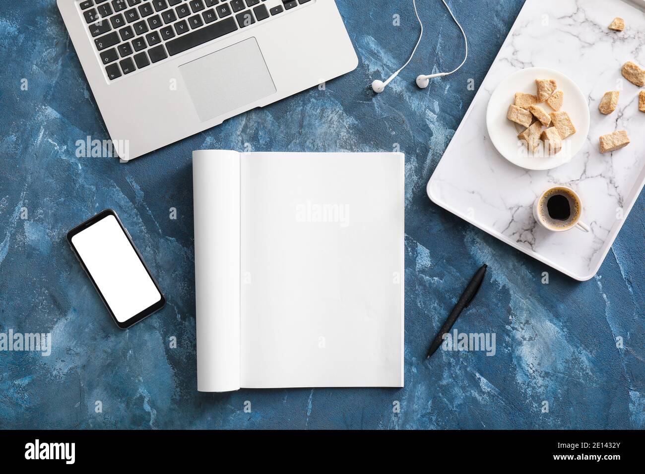 Blank magazine, laptop, mobile phone and tray with breakfast on color ...