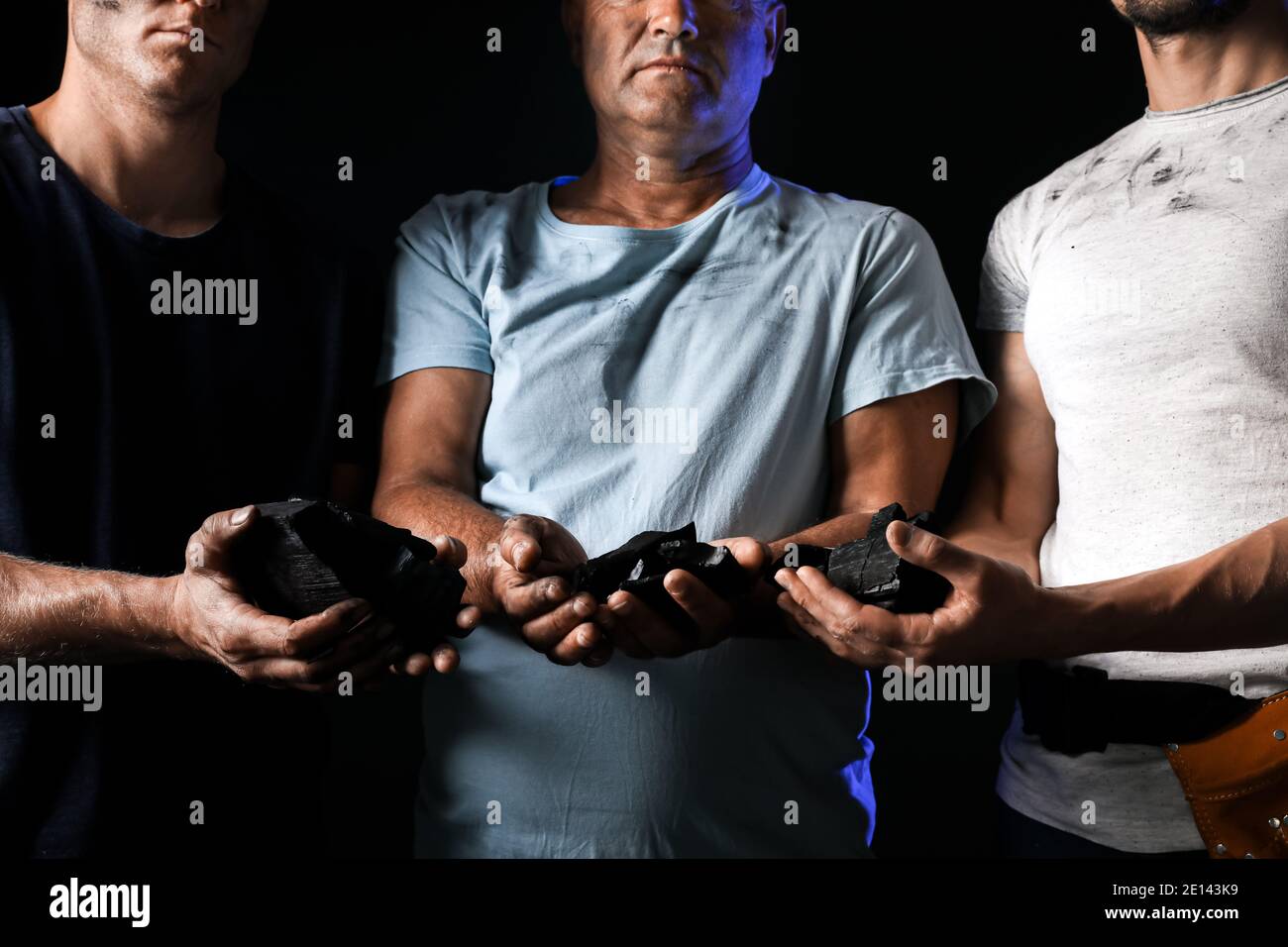 Miner men with coal on dark background Stock Photo - Alamy