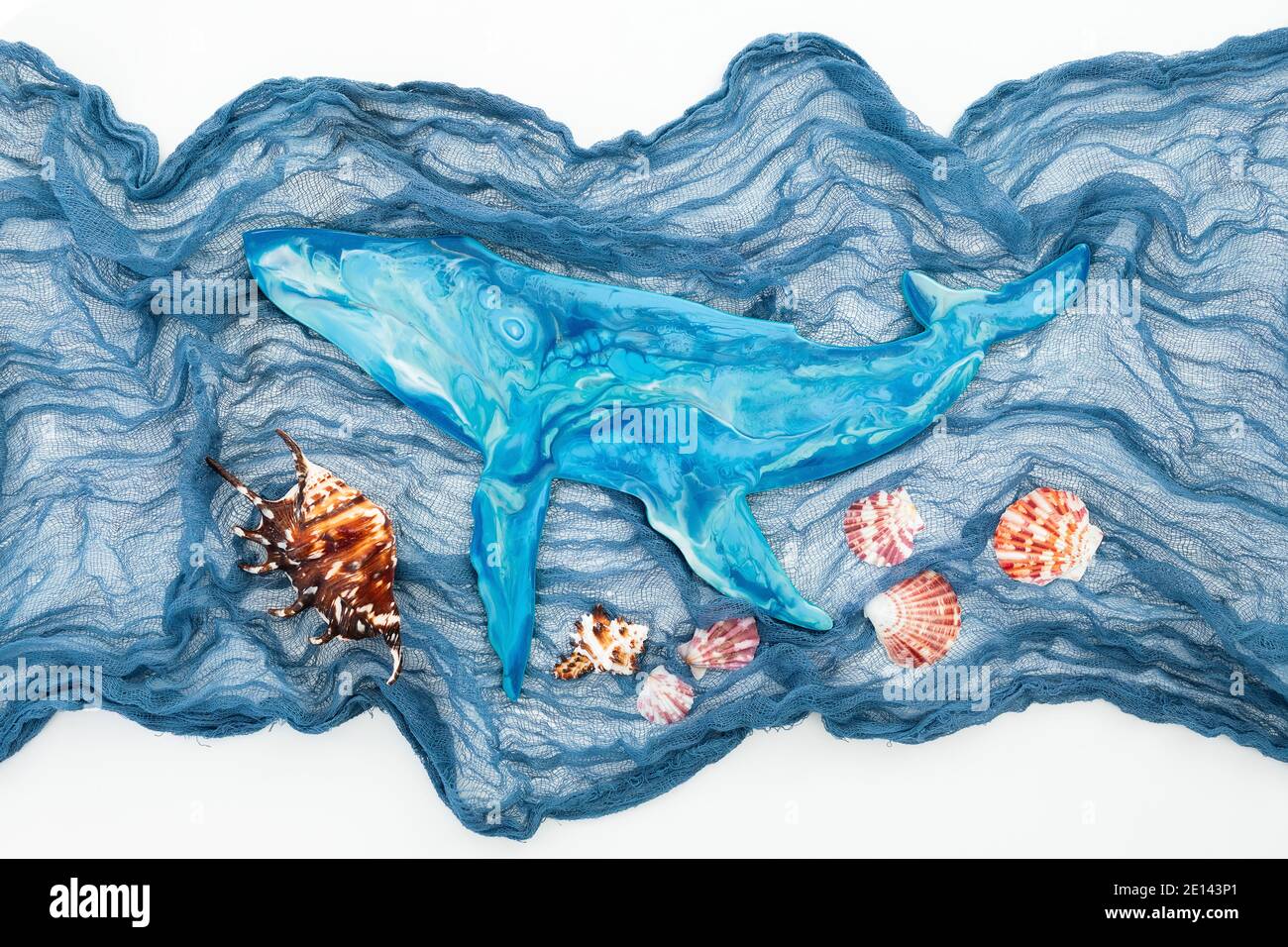 Resin art blue whale with fabric and sea shells on white background ...
