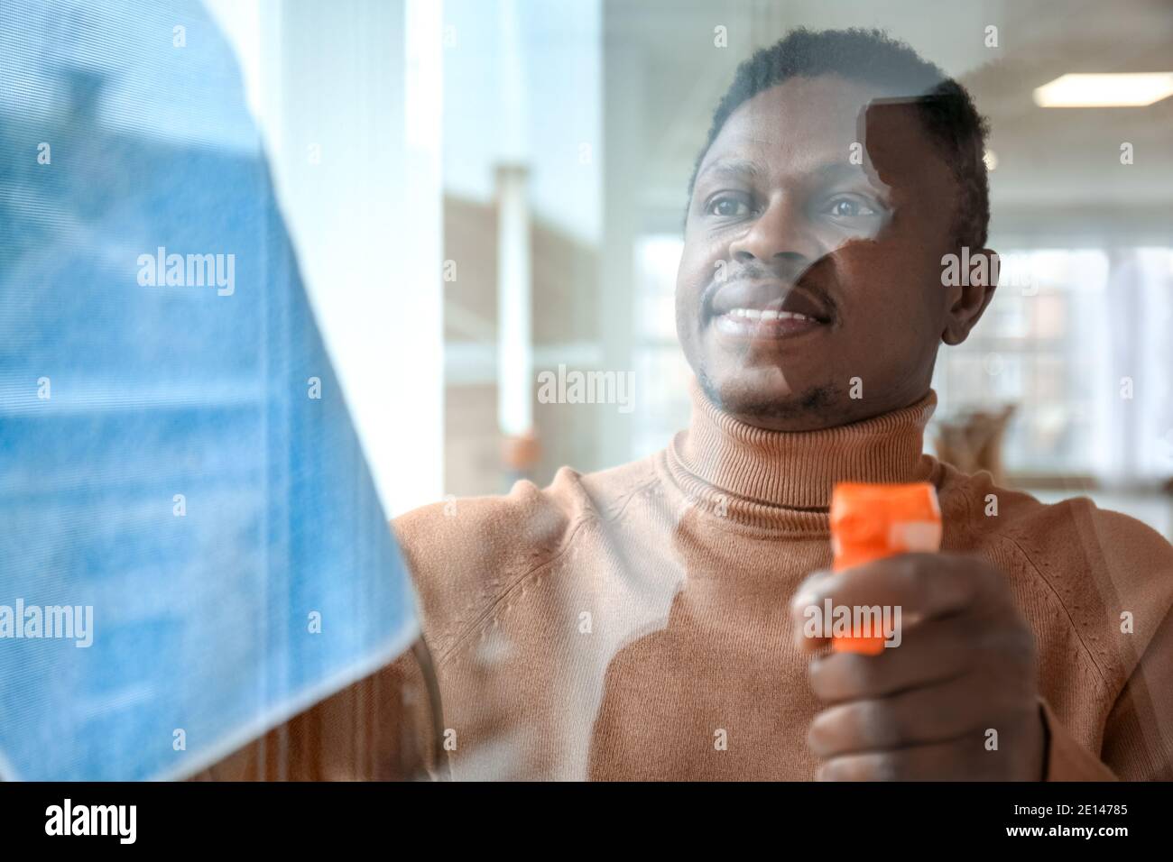 African-American man cleaning window in his flat Stock Photo - Alamy