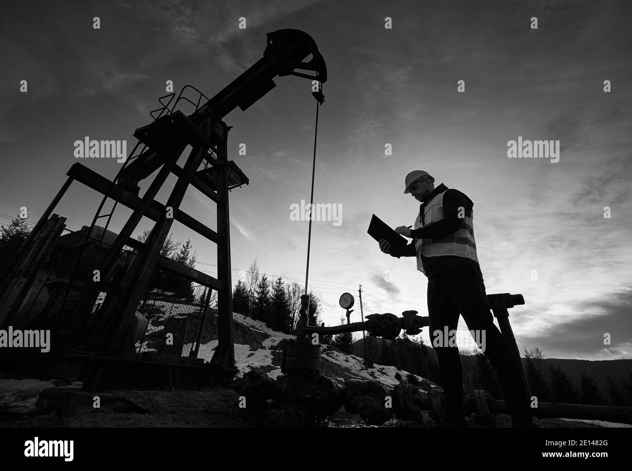 Low angle of petroleum engineer looking at oil pump rocker-machine and ...