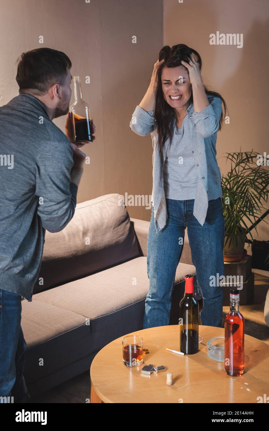 depressed, drunk woman touching head while standing with closed eyes ...