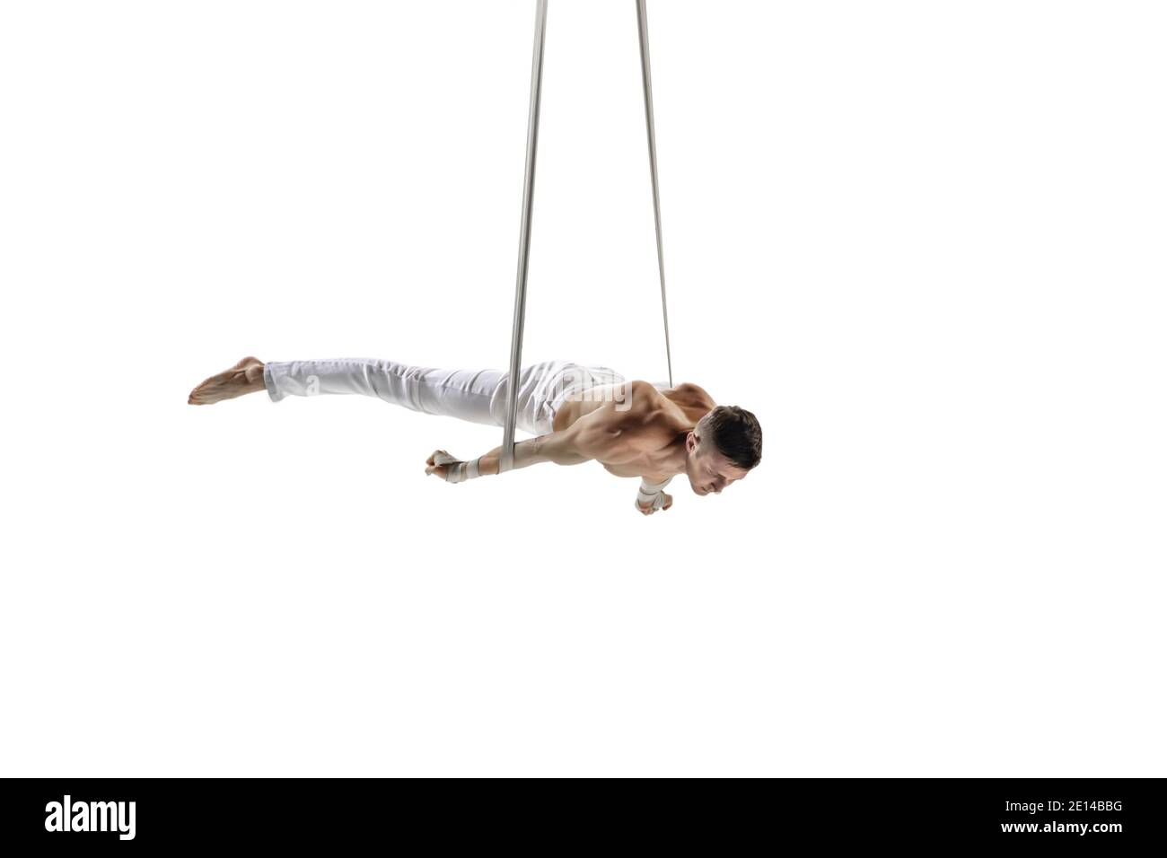 Strong. Young male acrobat, circus athlete isolated on white studio ...