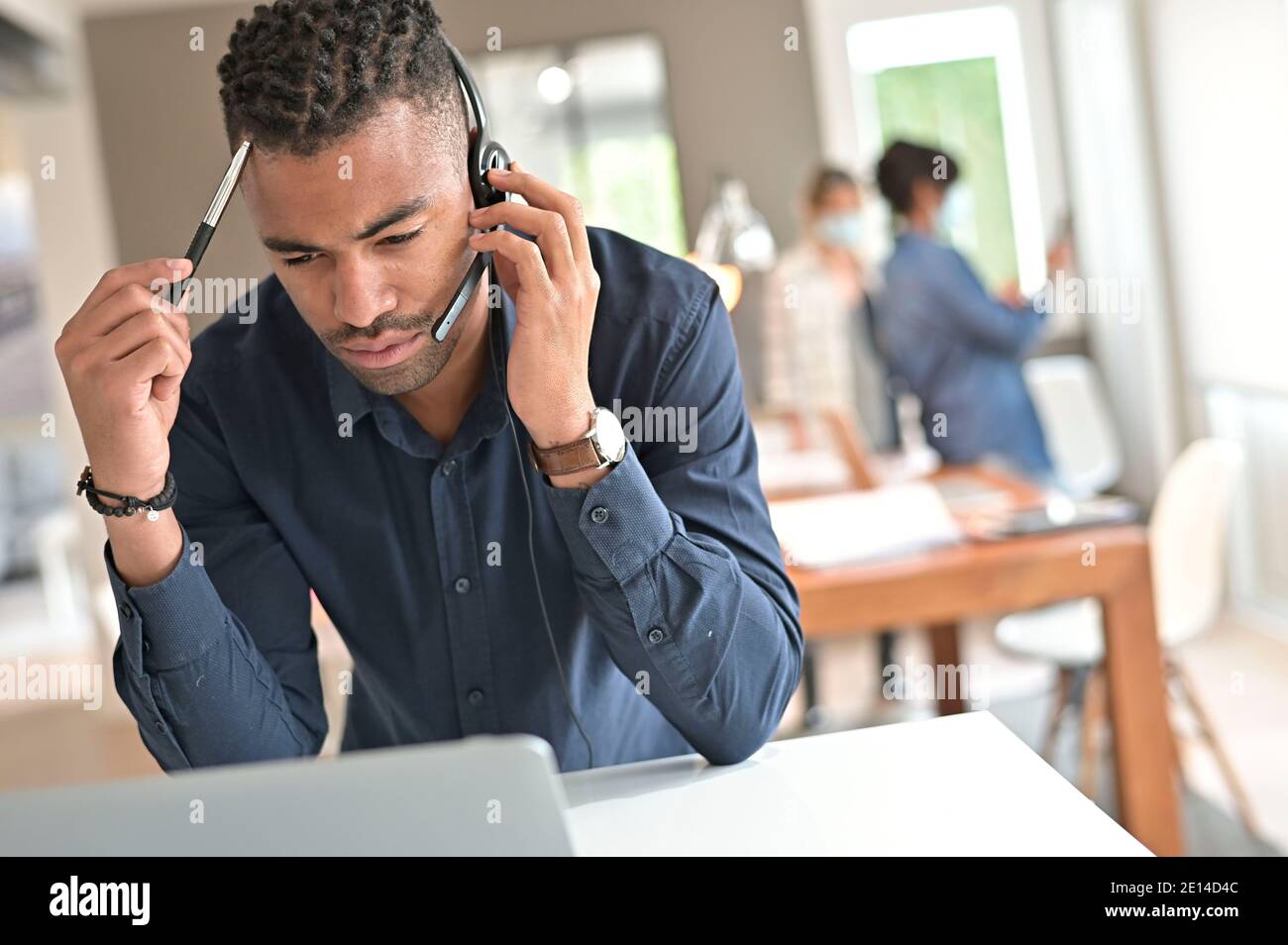 Salesman in co-working office with headsst working on laptop in open ...